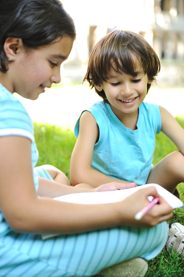 Two kids writing together outdoor - Year Round Homeschooling